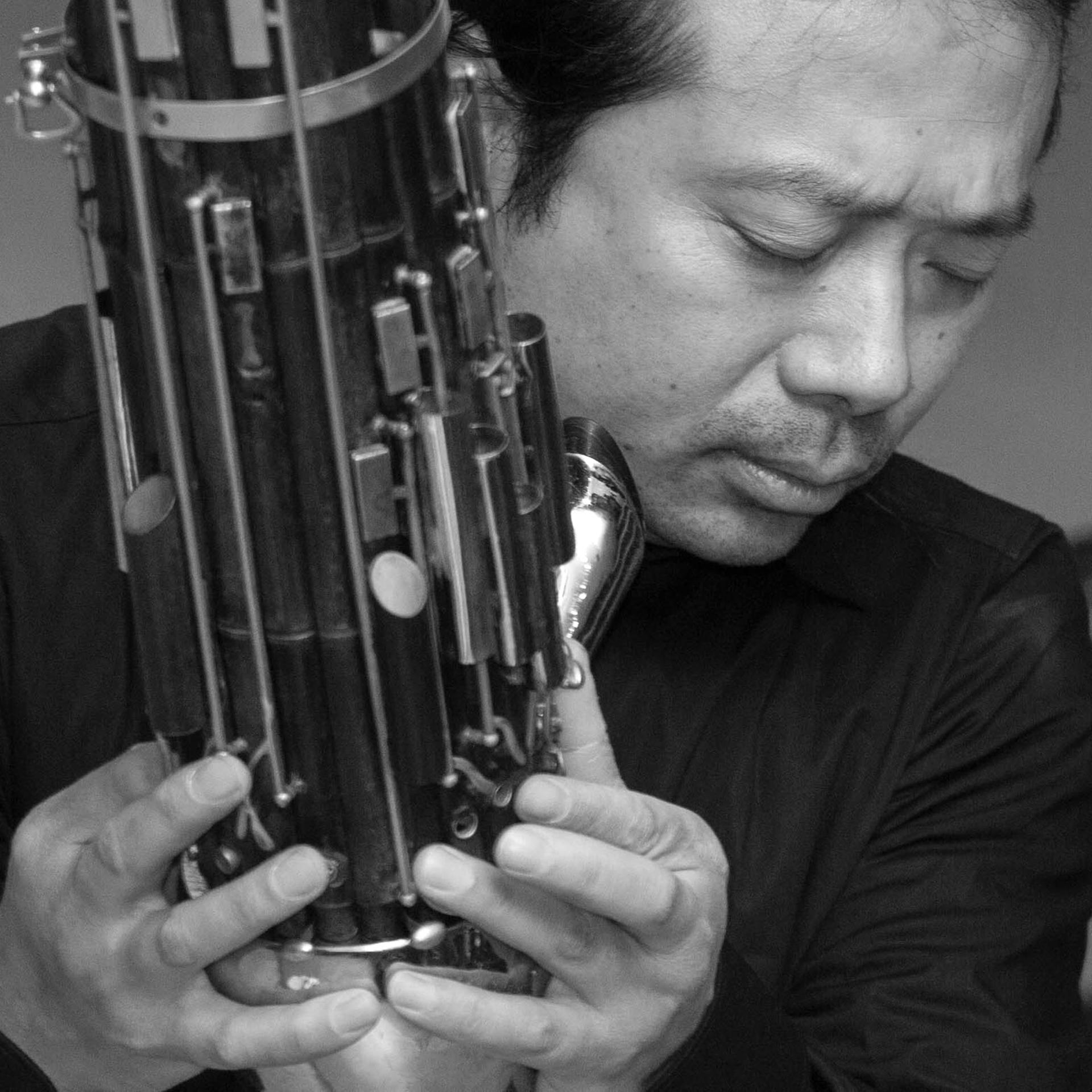 Ein Mann hält die Sheng vor sich, während er versunken den Kopf etwas ...